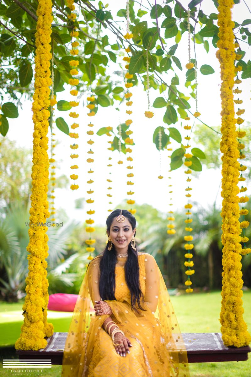 Photo of Haldi decor idea with bride sitting on the swing