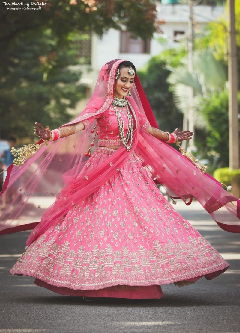 Photo of Sikh bride in bright pink lehenga twirling