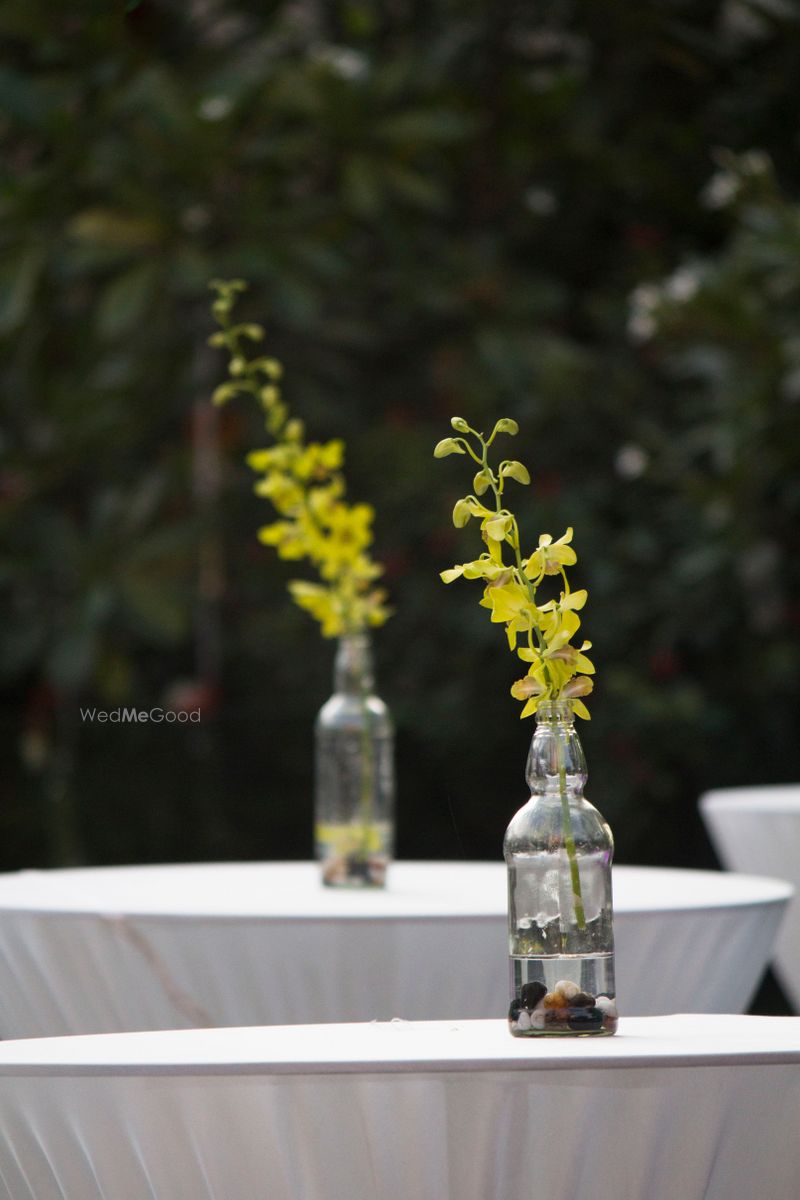 Photo Of Glass Bottles With Pebbles And Flowers As Centerpiece