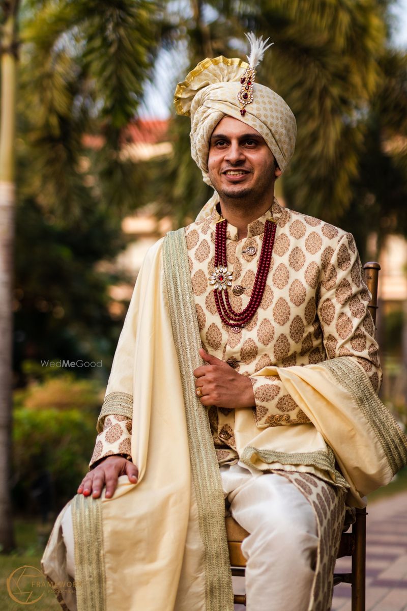 Photo of A happy portrait of a groom dressed in a classic white & gold ...