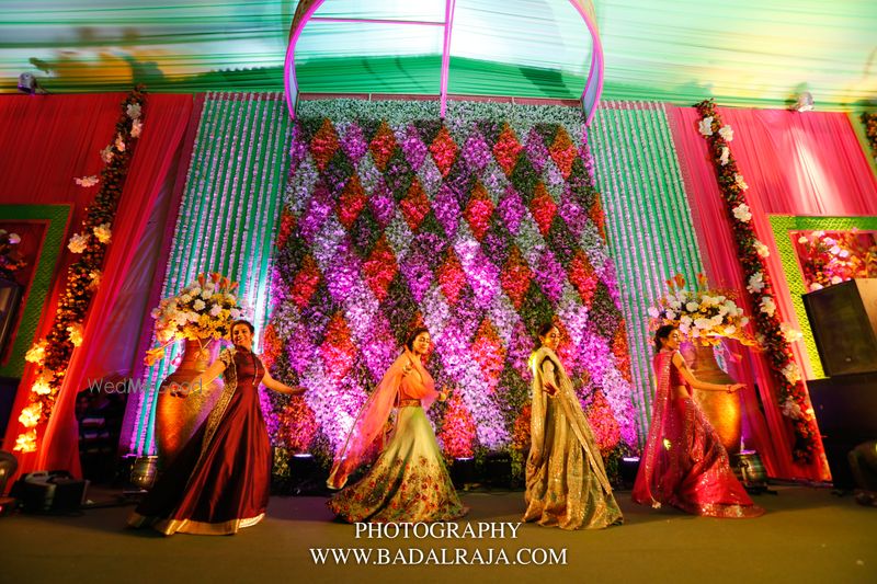 Photo of Bright and colorful floral stage backdrop for sangeet
