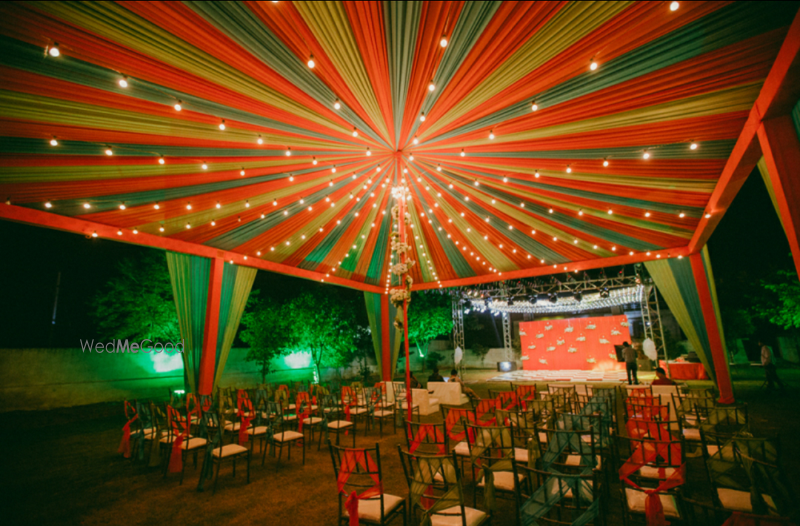 Photo of Bright and colourful mandap with drapes and fairy lights