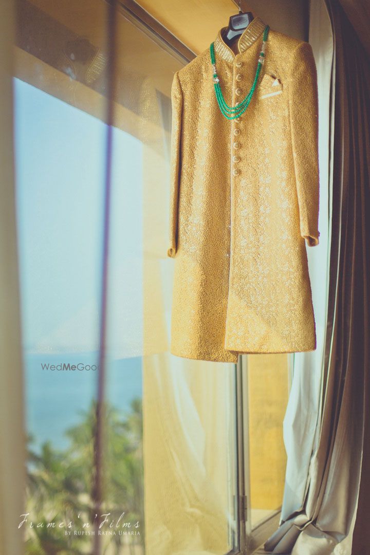 Photo of Gold Sherwani on a Hanger with Green Haar